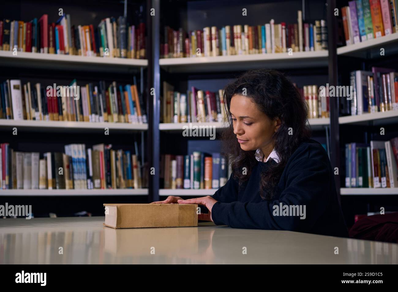 A woman deeply engrossed in reading a book, seated in the calm setting ...