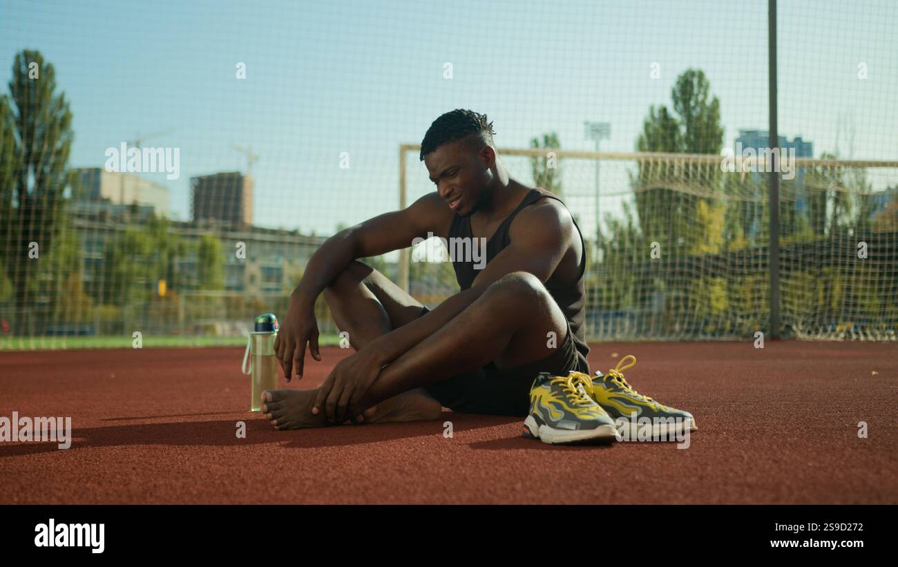 African American footballer sportsman sit on field suffer pain sharp ...