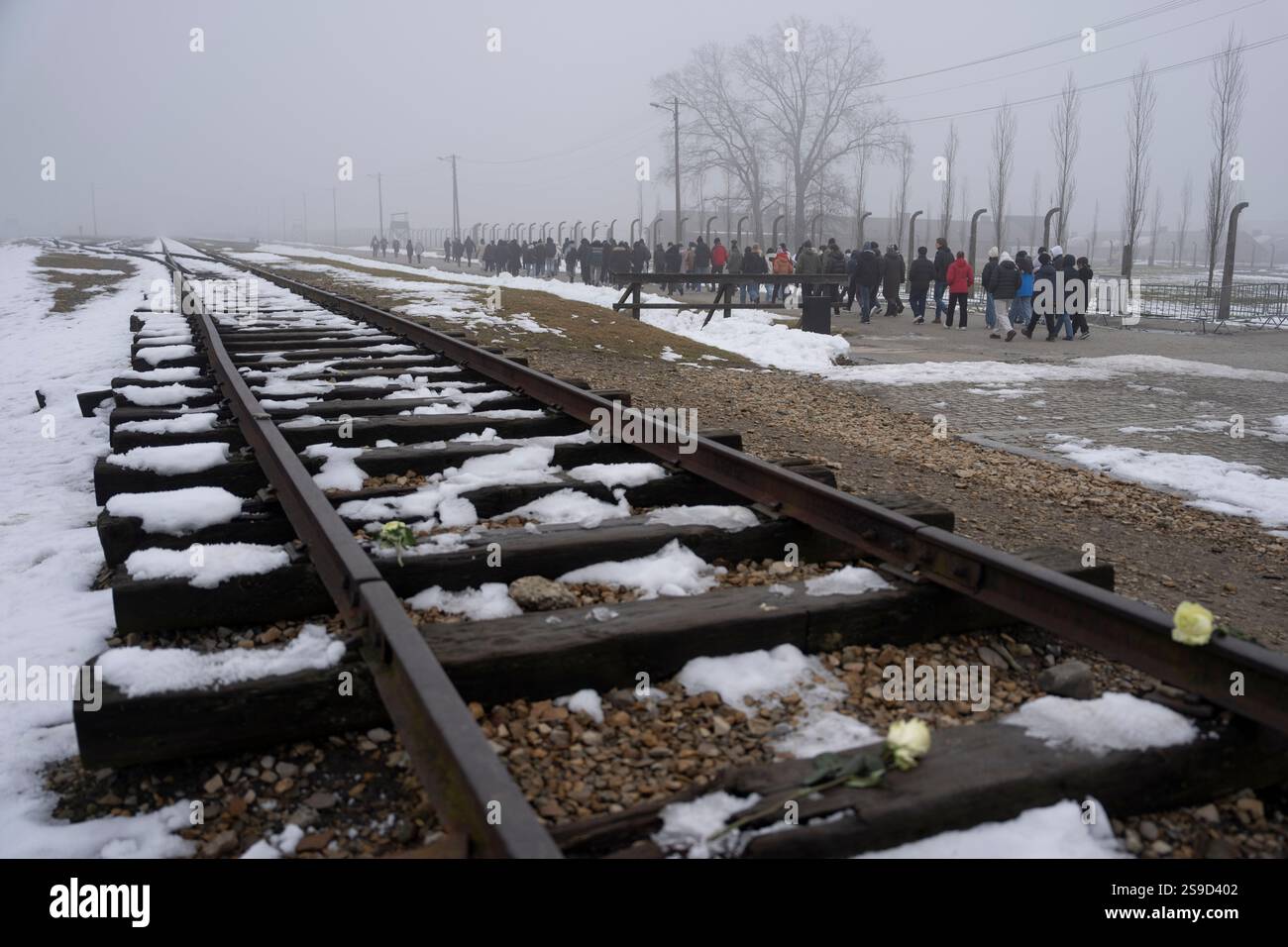Visitors walk along the old railroad tracks once used to transport Jews ...
