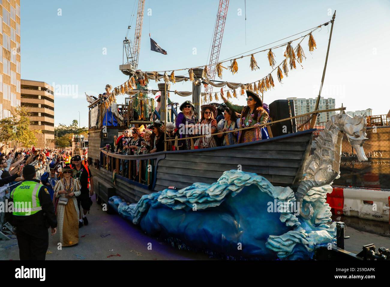 Parade participants ride on a float while they toss beads into the ...