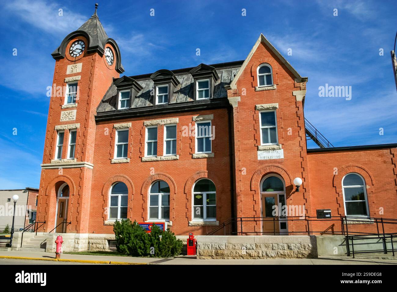 A brick building with a clock tower and a red fire hydrant in front ...