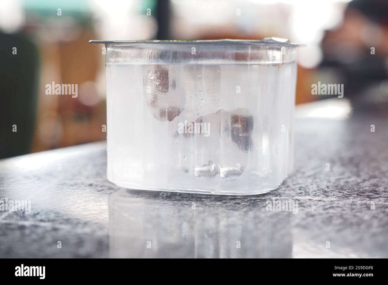 A clear container filled with water placed on a marble surface Stock ...