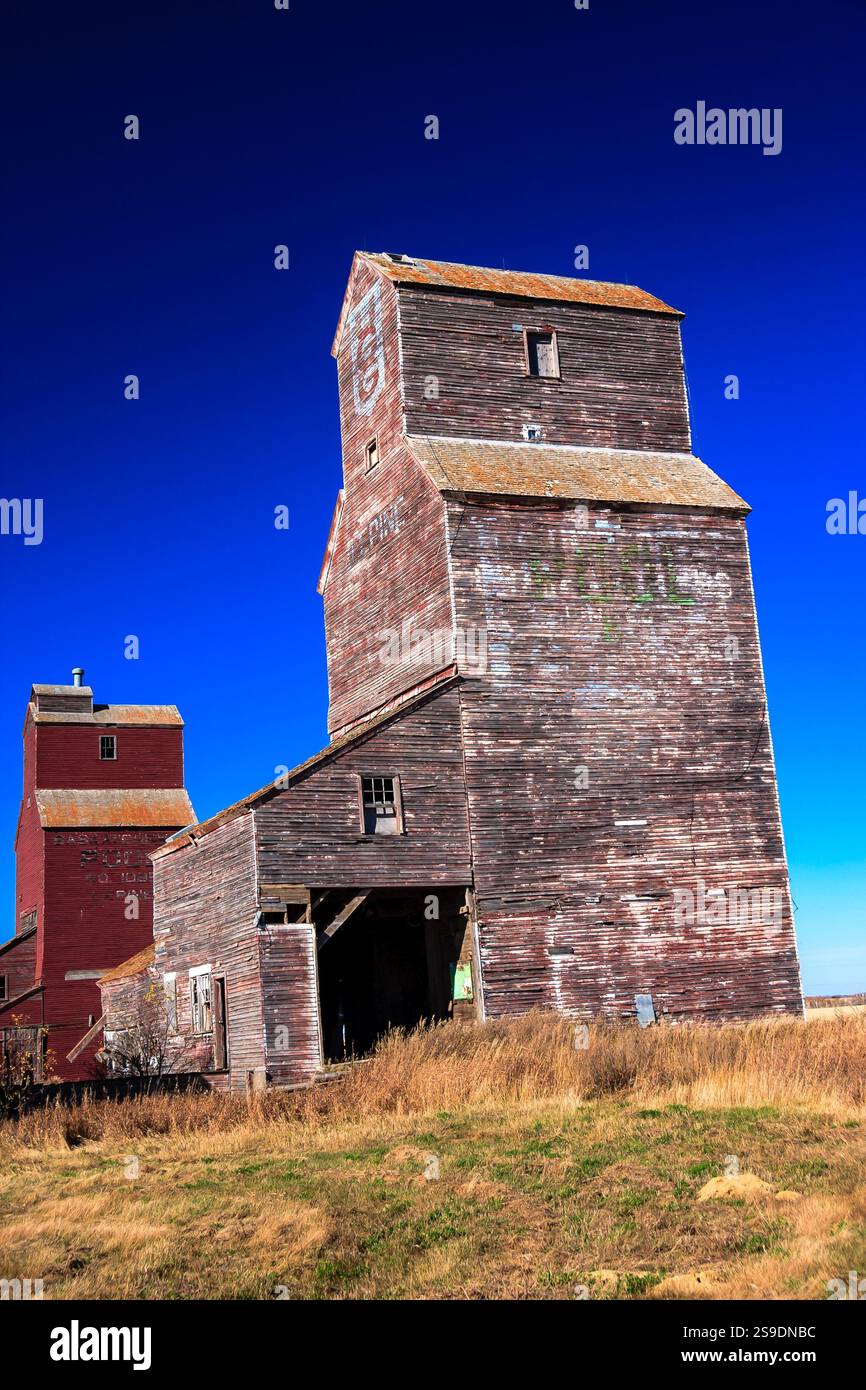 A large, old grain silo is surrounded by a field. The silo is empty and ...