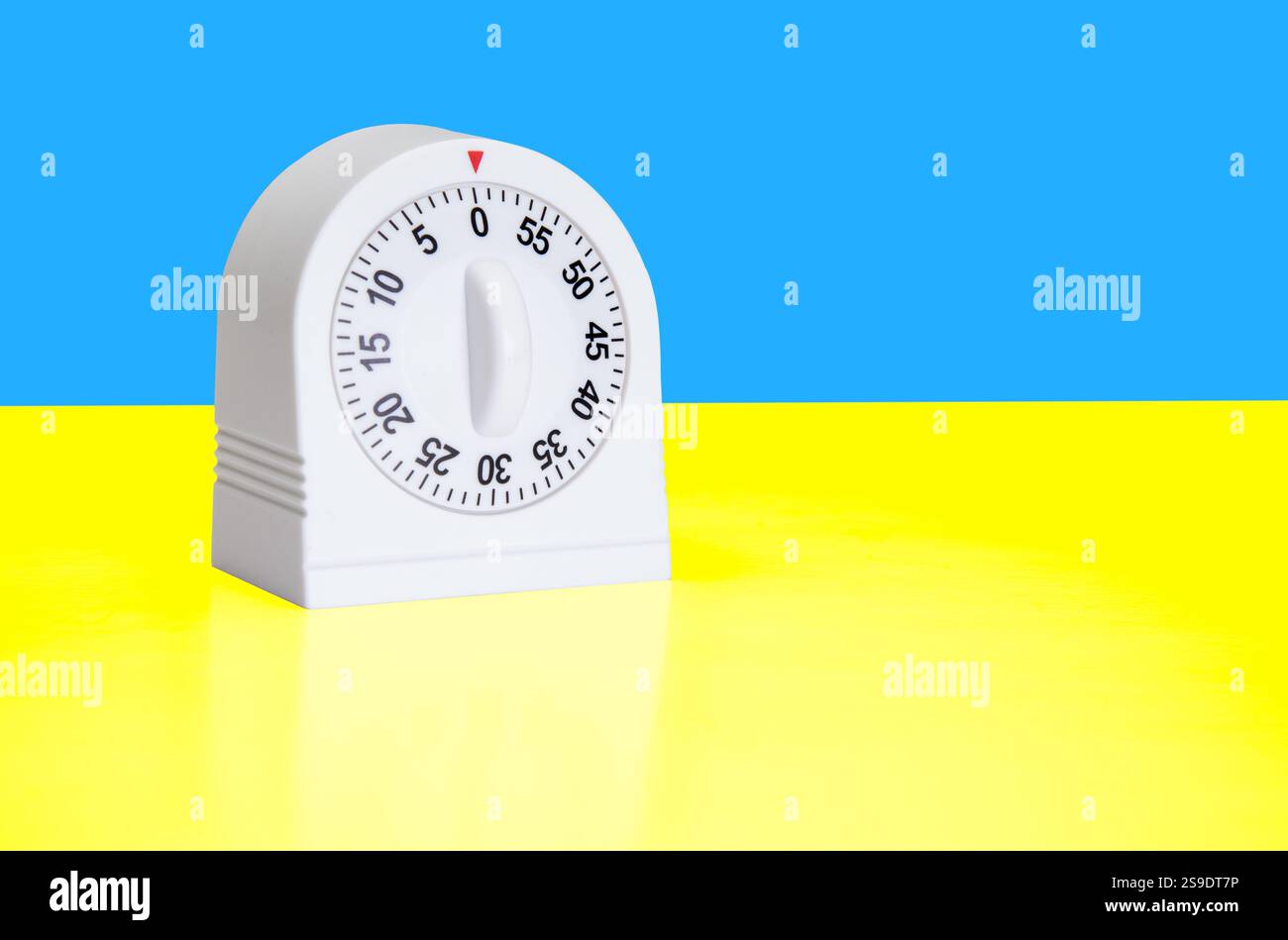 A mechanical white kitchen timer is displayed on a bold and colorful ...