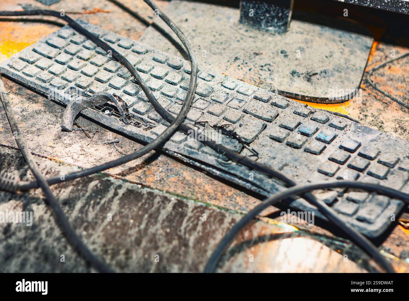 Burnt and dust covered keyboard with tangled cables, lying amid debris ...