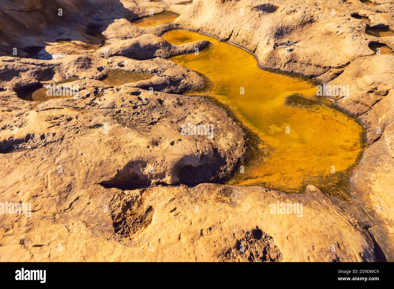 Natural rock formations with shallow pools of water which have a ...
