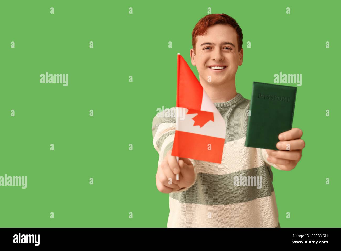 Handsome young happy man with Canadian flag and passport on green ...