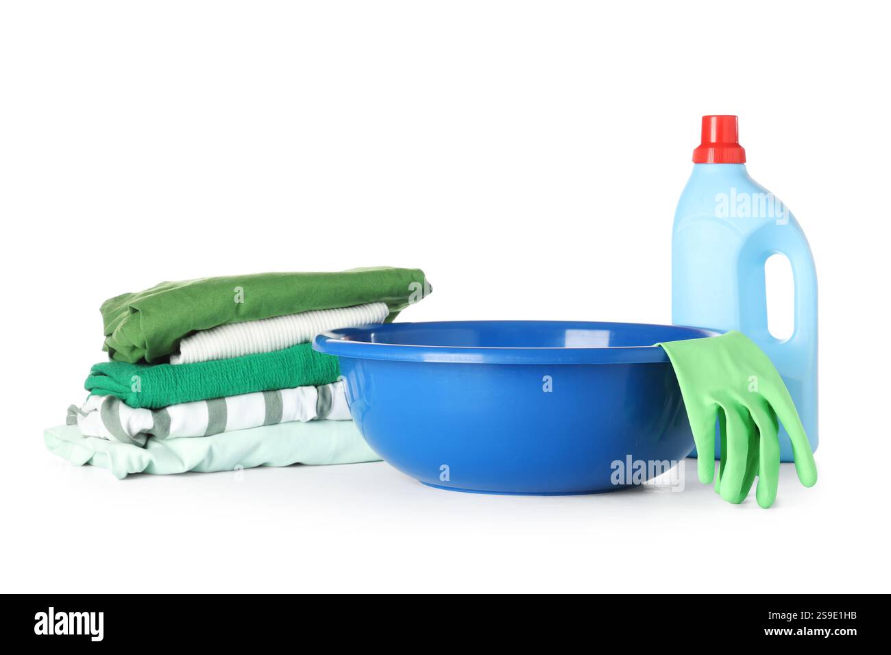 Plastic basin, clean laundry and bottle of detergent on white ...