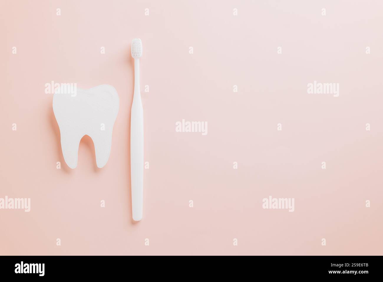 A paper tooth and toothbrush on pastel pink for Dentist Day concept ...
