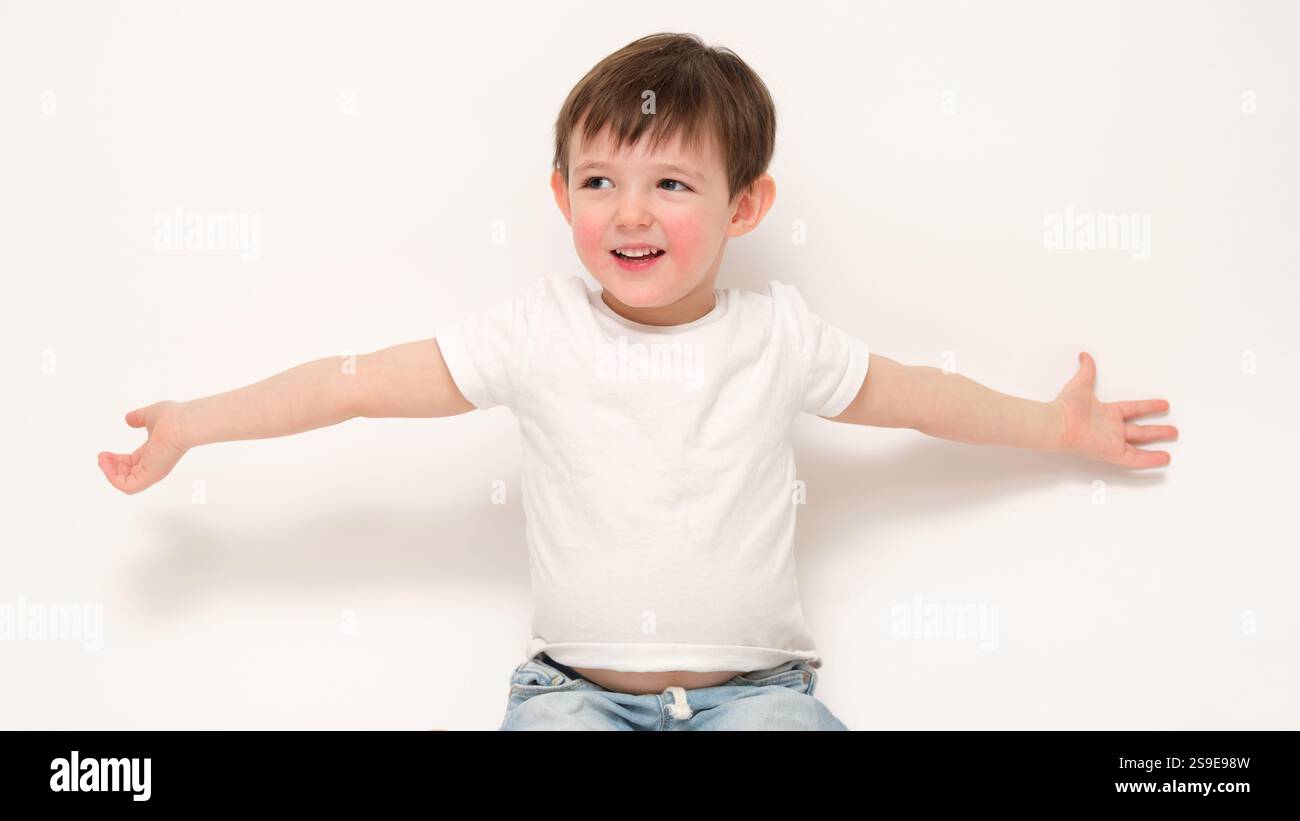 Smiling child in a white t-shirt with arms outstretched on a white ...