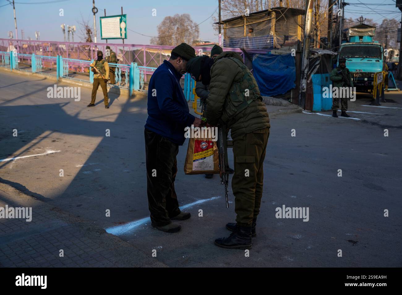 An Indian policeman searches the bag of a person at a checkpoint during ...