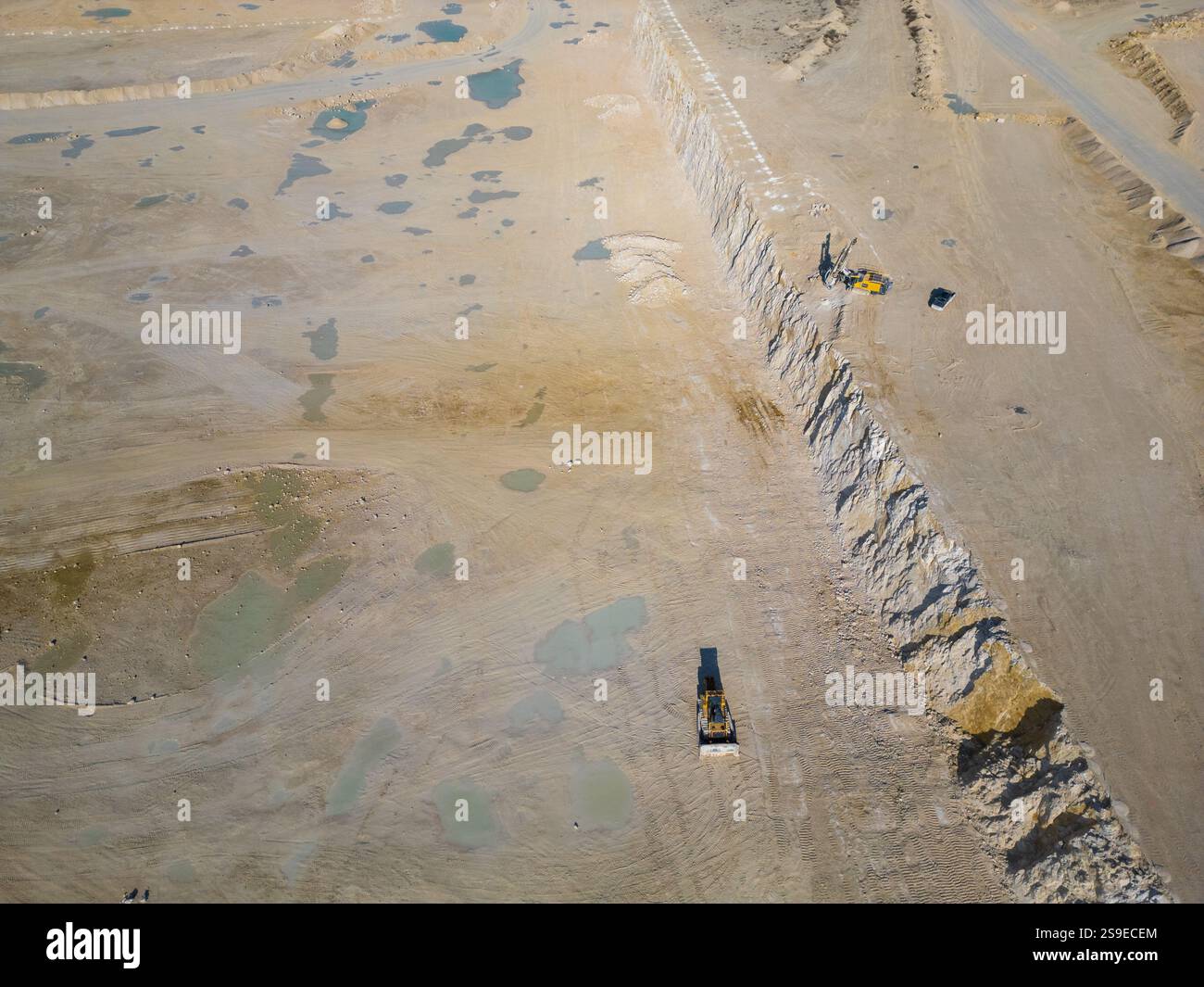 An open-pit quarry with terraced layers and heavy machinery operating ...