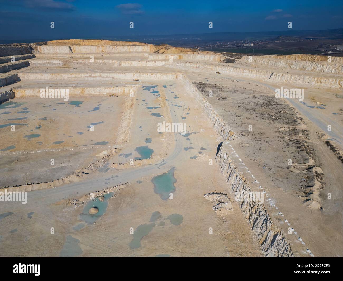 An open-pit quarry with terraced layers and heavy machinery operating ...