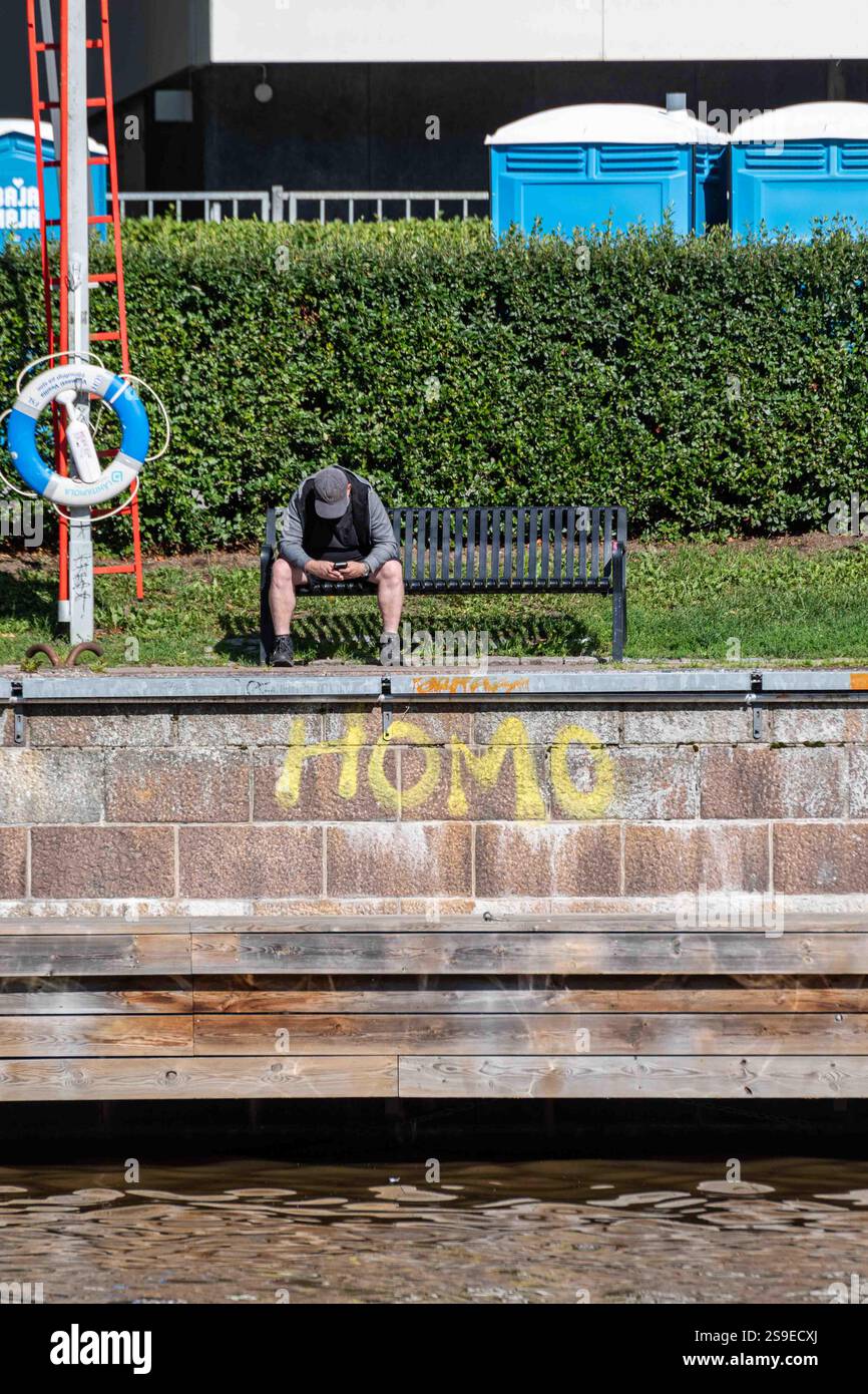 Man sitting on a park bench by the Aura River in Turku, Finland ...