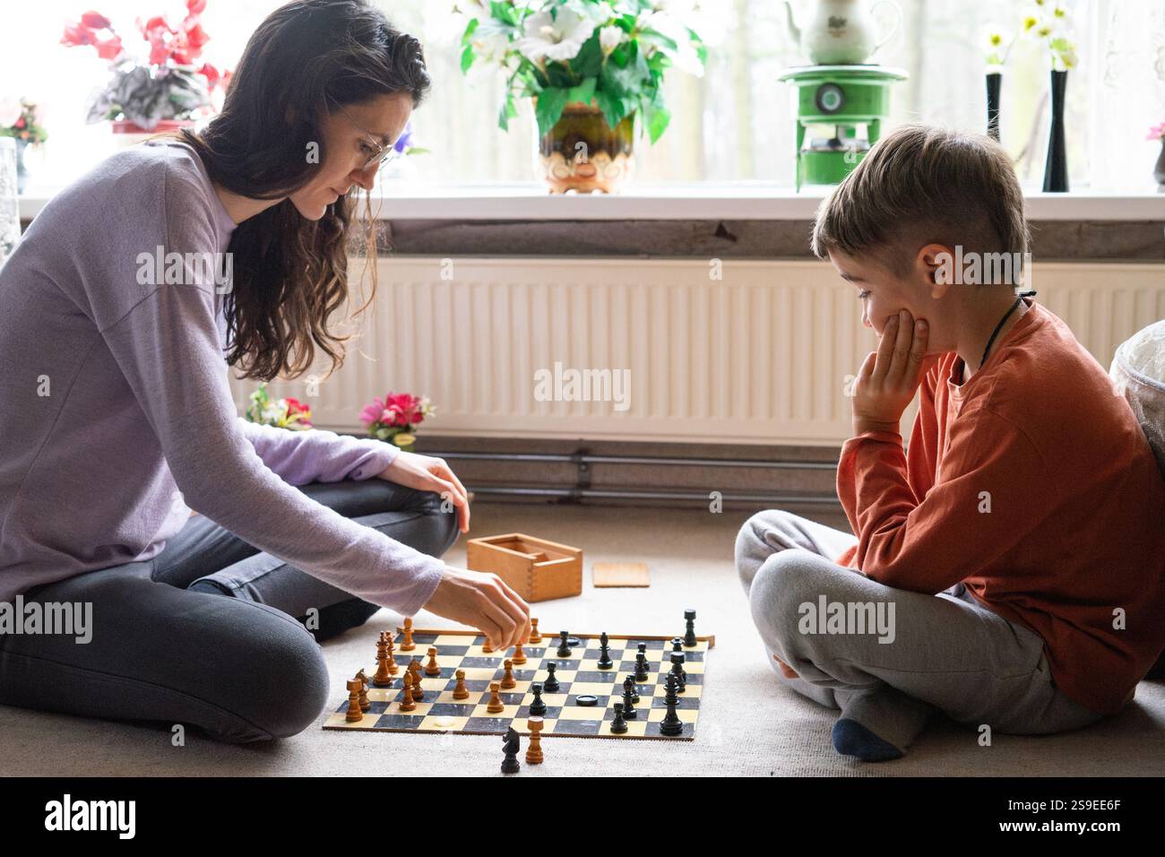 Mom and son enjoying a game of chess, fostering bonding and strategic ...