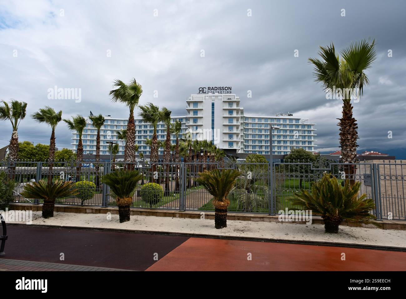 Modern hotel with palm trees and cloudy sky in a coastal location ...