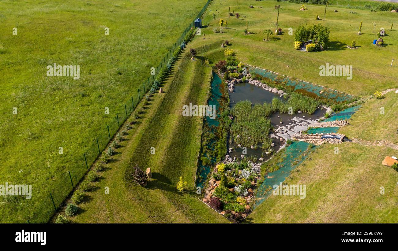 Aerial view of a landscaped garden with a pond, surrounded by grass and ...