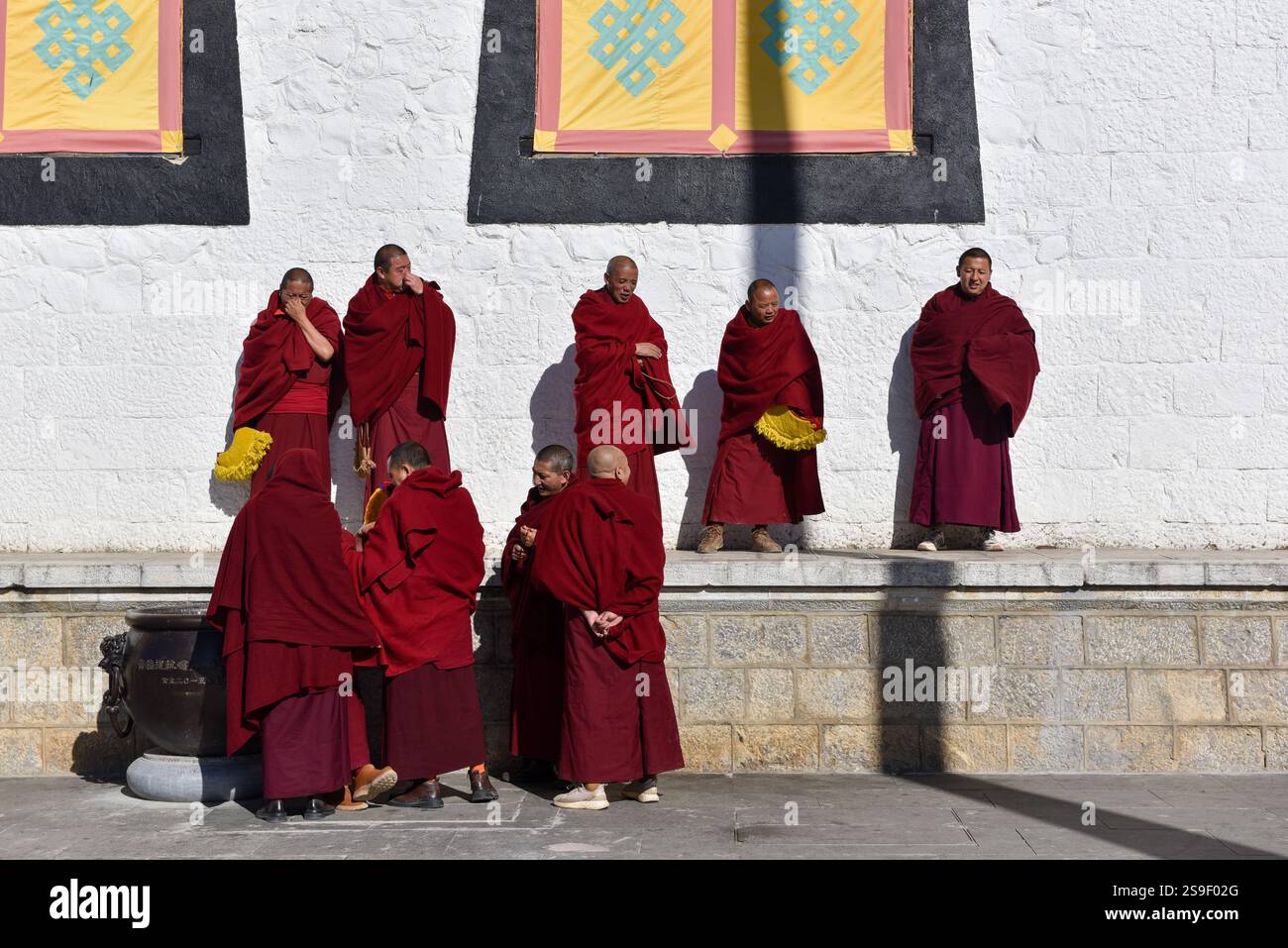 Tibetan buddhist monks basking in the sun outside Ganden Sumtsenling ...