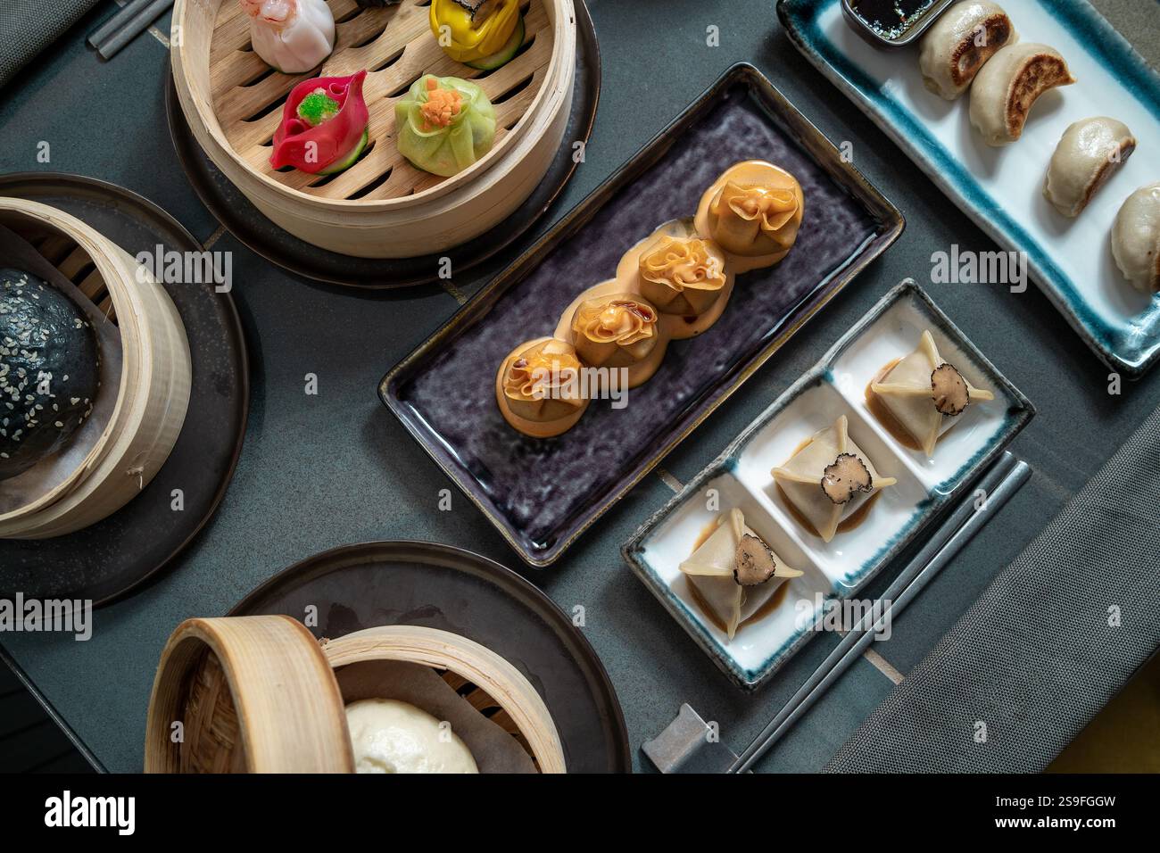 A top view of assorted dim sum served in bamboo steamers and ceramic ...