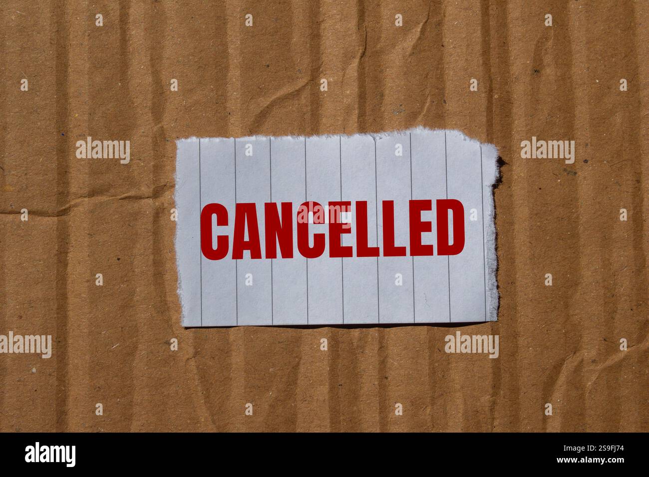 Cancelled message written on ripped torn paper piece with cardboard ...