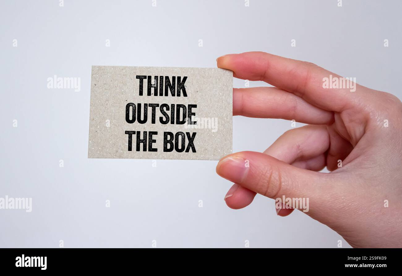 Think outside the box message written on a card in hand. Conceptual ...