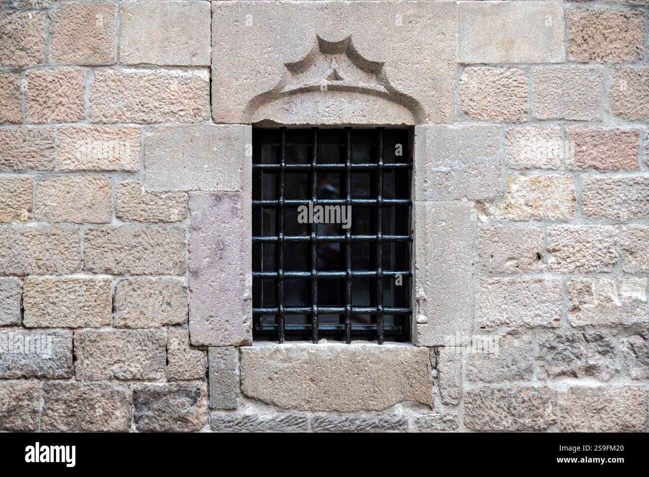 Rectangular window with black cast iron grille on old beige stone wall ...