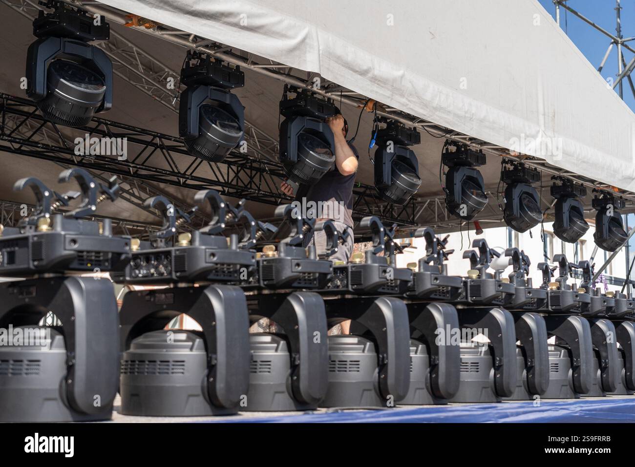 Installation of lighting equipment on a mobile concert stage. A worker ...