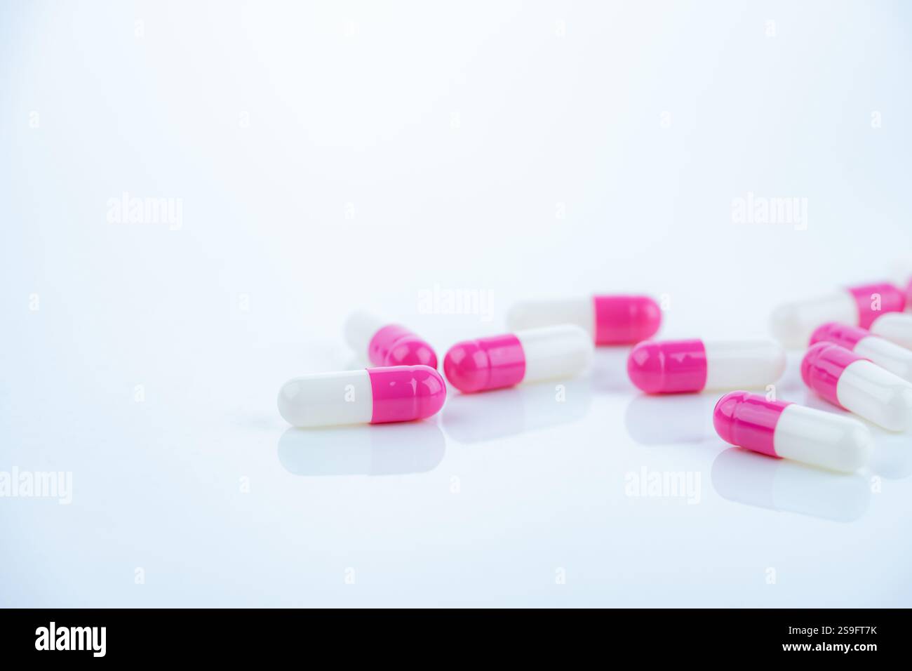 Pink-white antibiotic capsules spread on white background. Prescription ...
