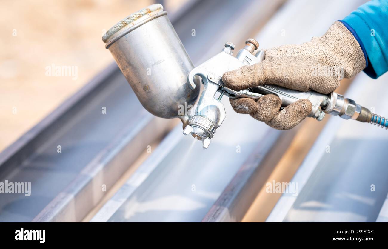 Construction worker painting metal structure surface coating with a ...