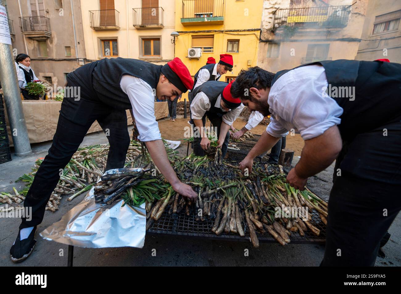 Several people participate in the roasting of calçots during the Festa ...