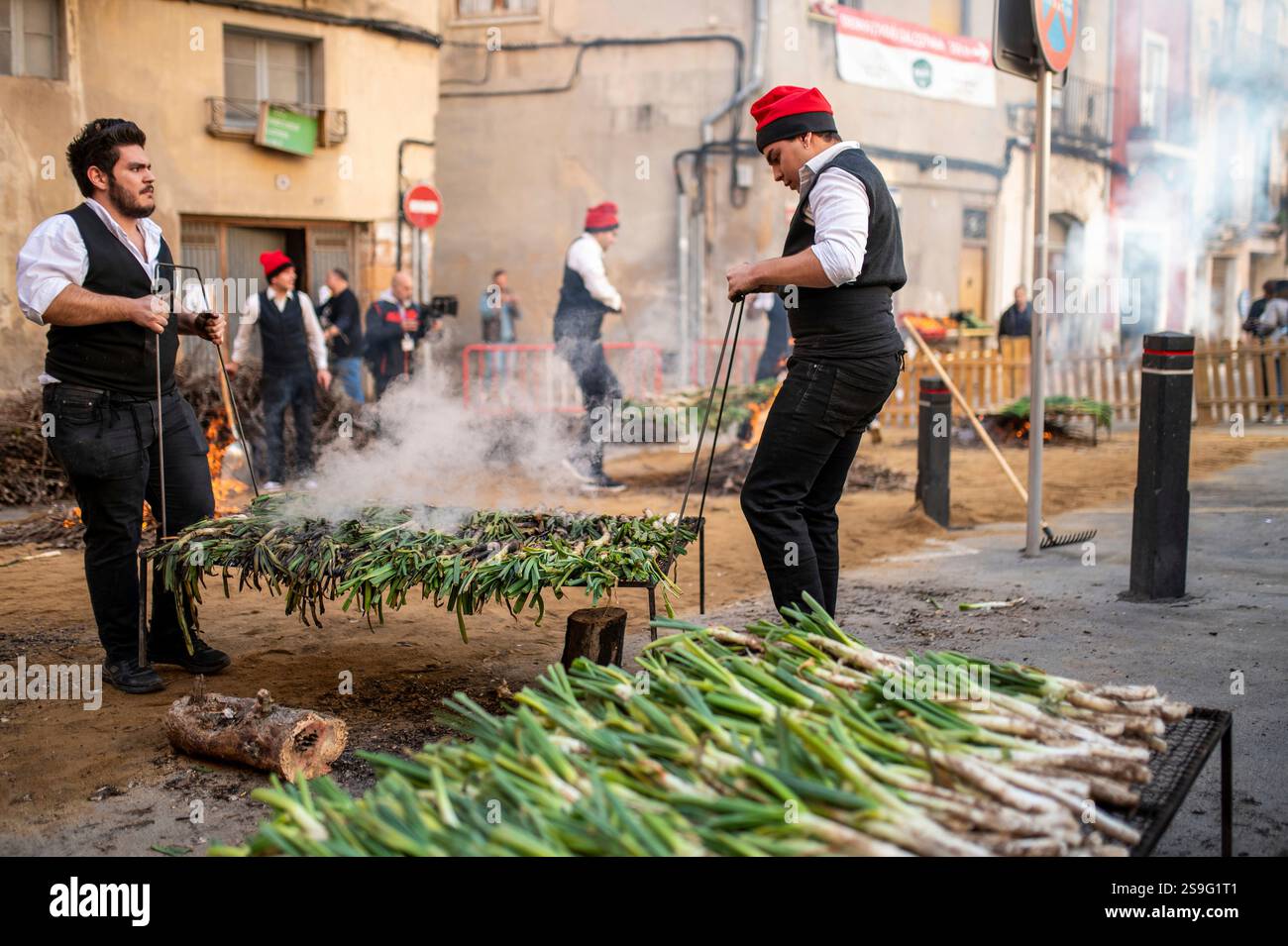 Several people participate in the roasting of calçots during the Festa ...
