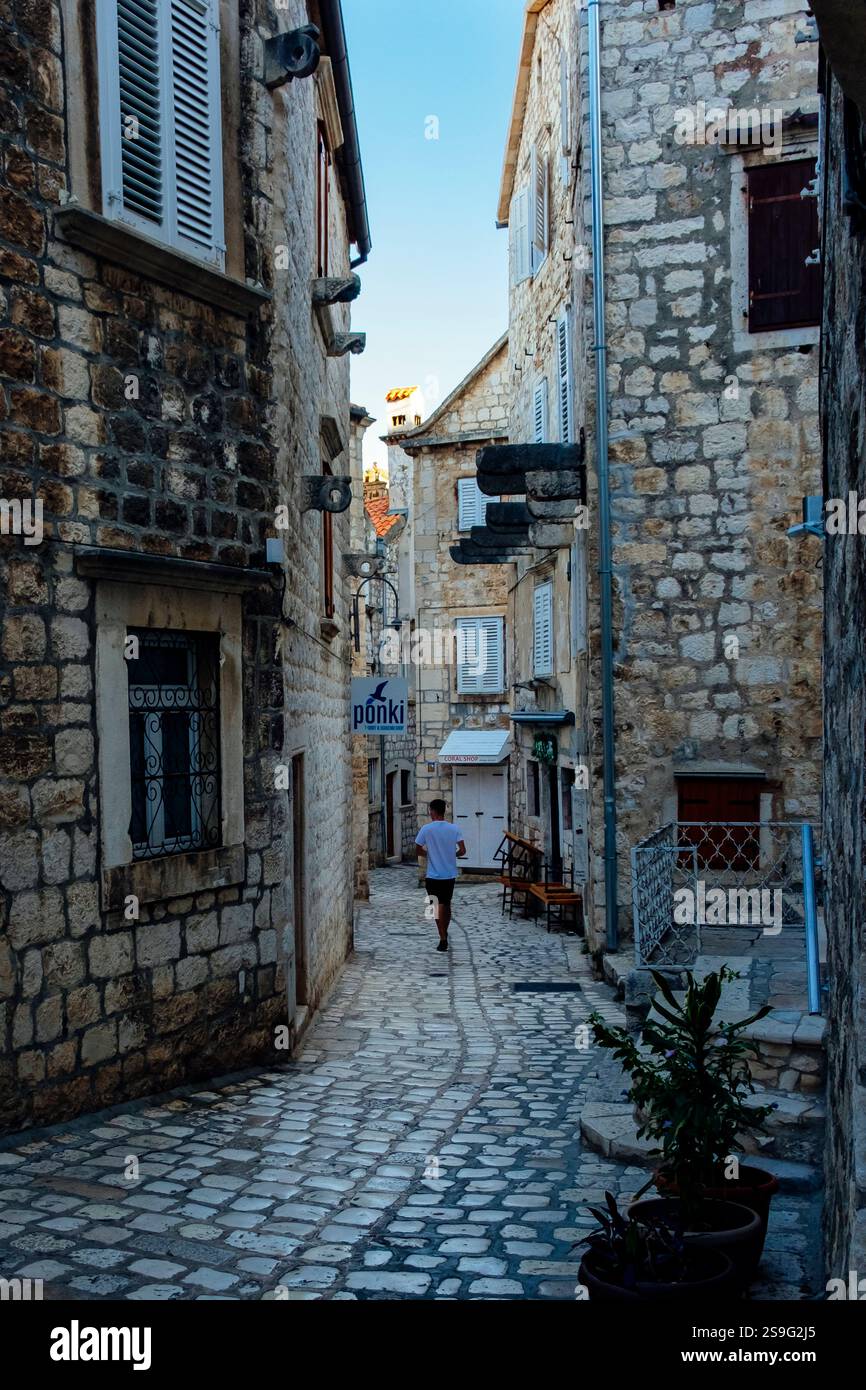 Tourist walking along cobbled street & old buildings of Old Town Hvar ...