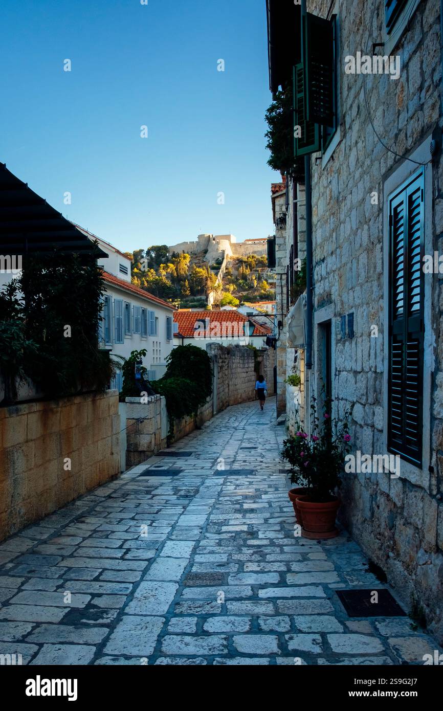 Tourist walking along cobbled street & old buildings of Old Town Hvar ...