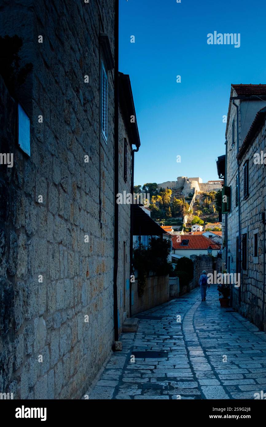 Tourist walking along cobbled street & old buildings of Old Town Hvar ...