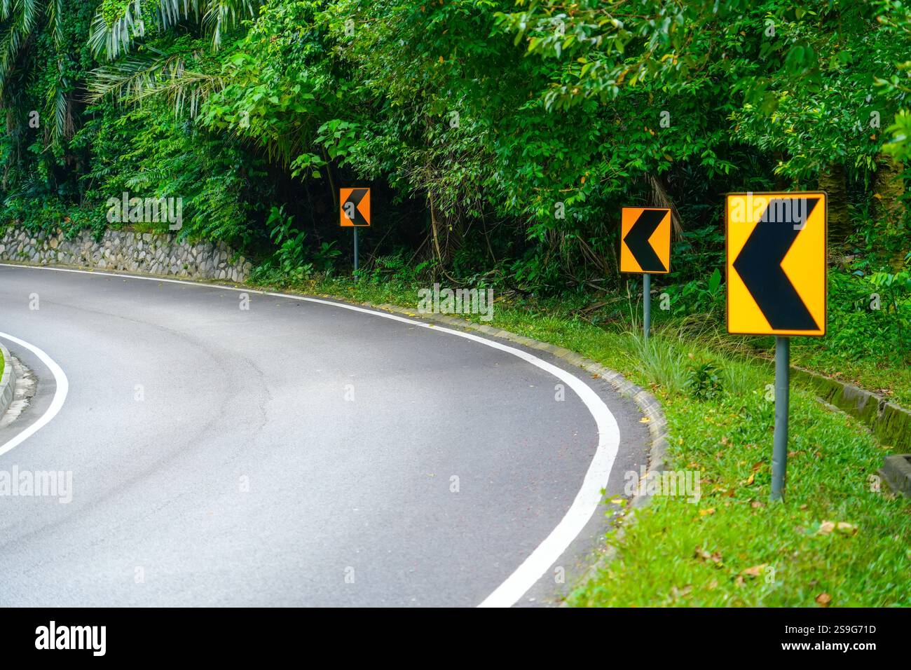 Sharp turn sign yellow warning attention road, serpentine. Car winding road in beautiful forest ...