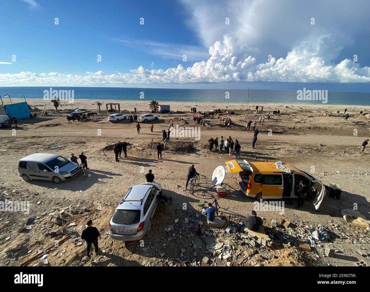 People gather by a banner welcoming people near the rubble of a ...