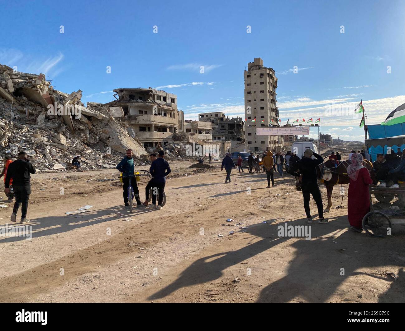 People gather by a banner welcoming people near the rubble of a ...