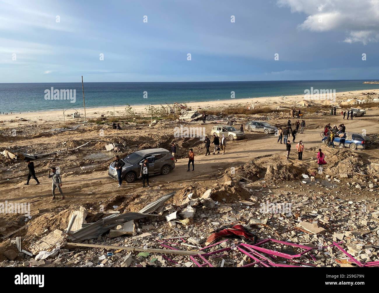 People gather by a banner welcoming people near the rubble of a ...