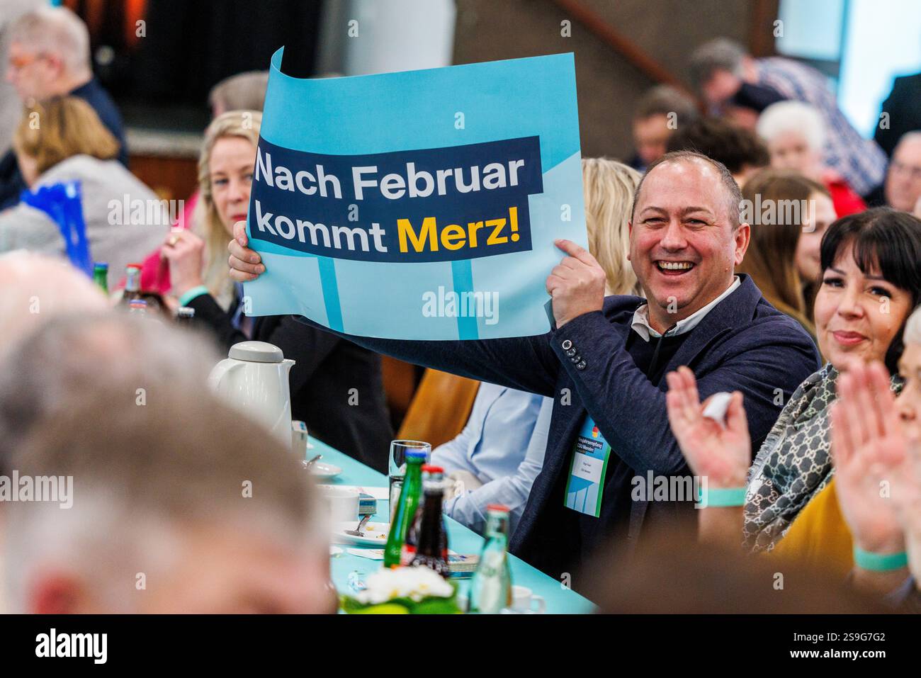 26 January 2025, North Rhine-Westphalia, Menden: A man shows a poster ...