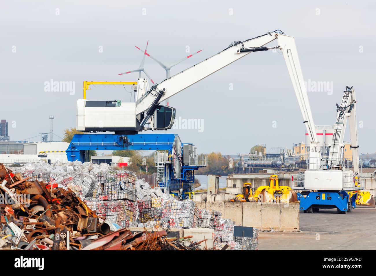 Crane at recycling facility loading large scrap metal pile with wind ...