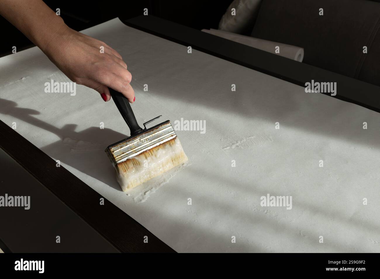Applying thick glue to wallpaper, brushing wallpaper before sticking it ...