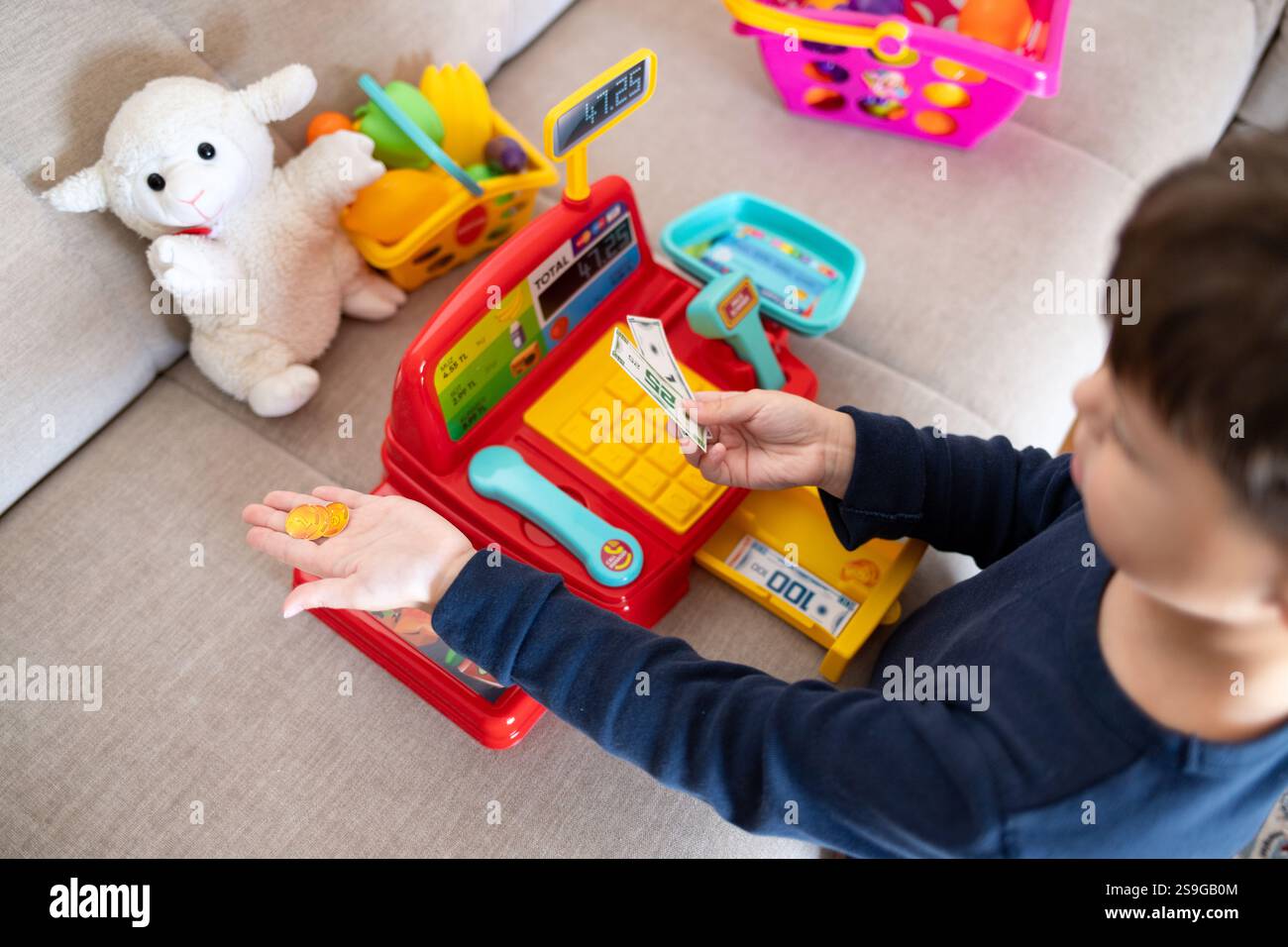 A boy is playing store with a toy cash register Stock Photo - Alamy