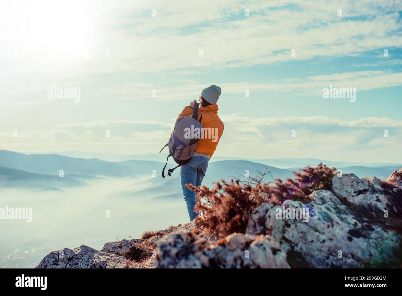 Cheering woman backpacker enjoy the view on sunrise mountain top cliff ...
