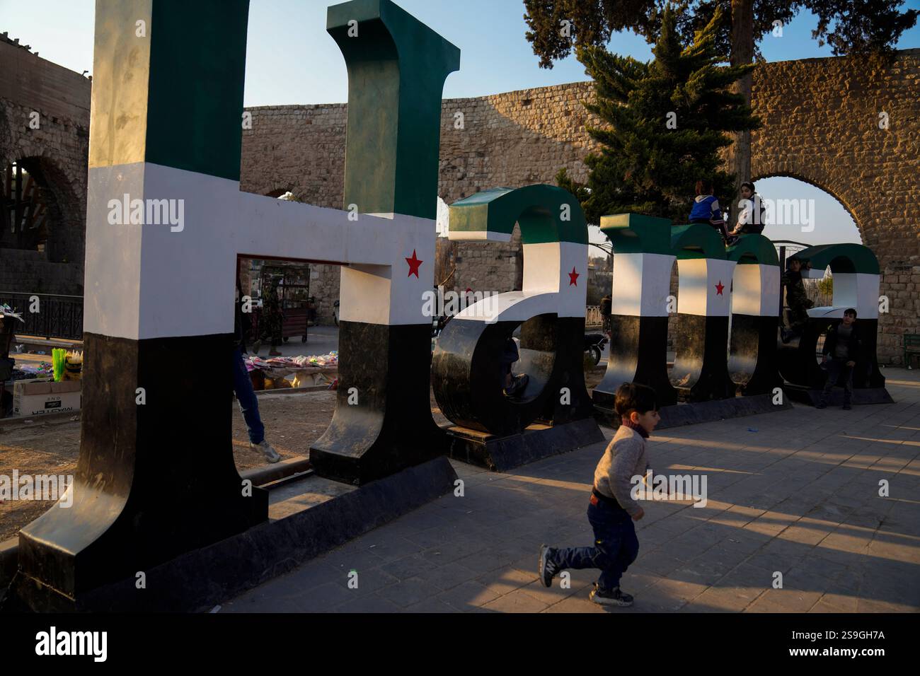 Children play on a model of the name of the city of Hama, painted in ...