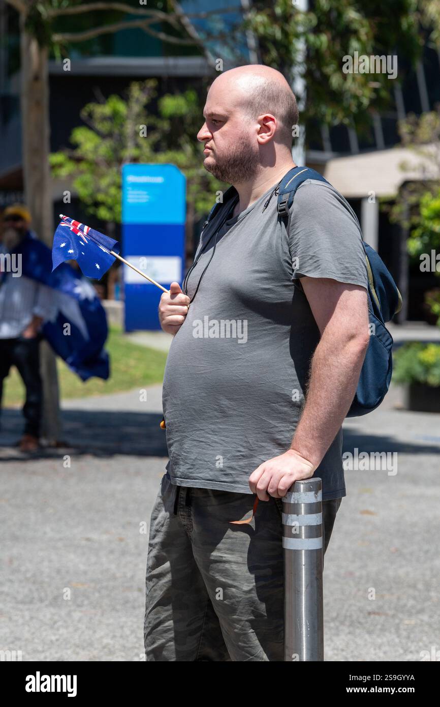 A man holds small Australian Flag as he watches speakers during a right ...