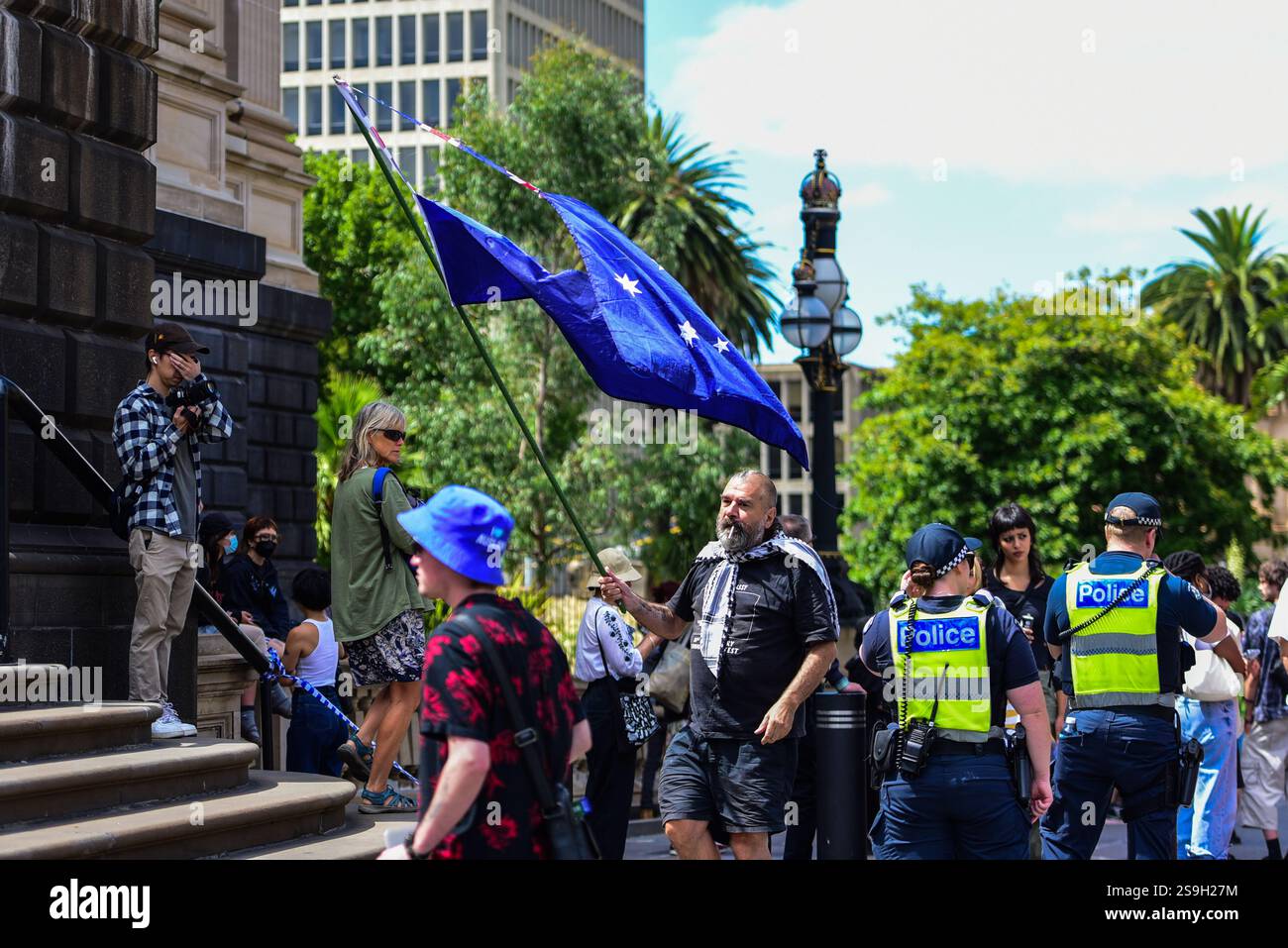 A protester waves an Australian flag with a cutout of the Union Jack ...
