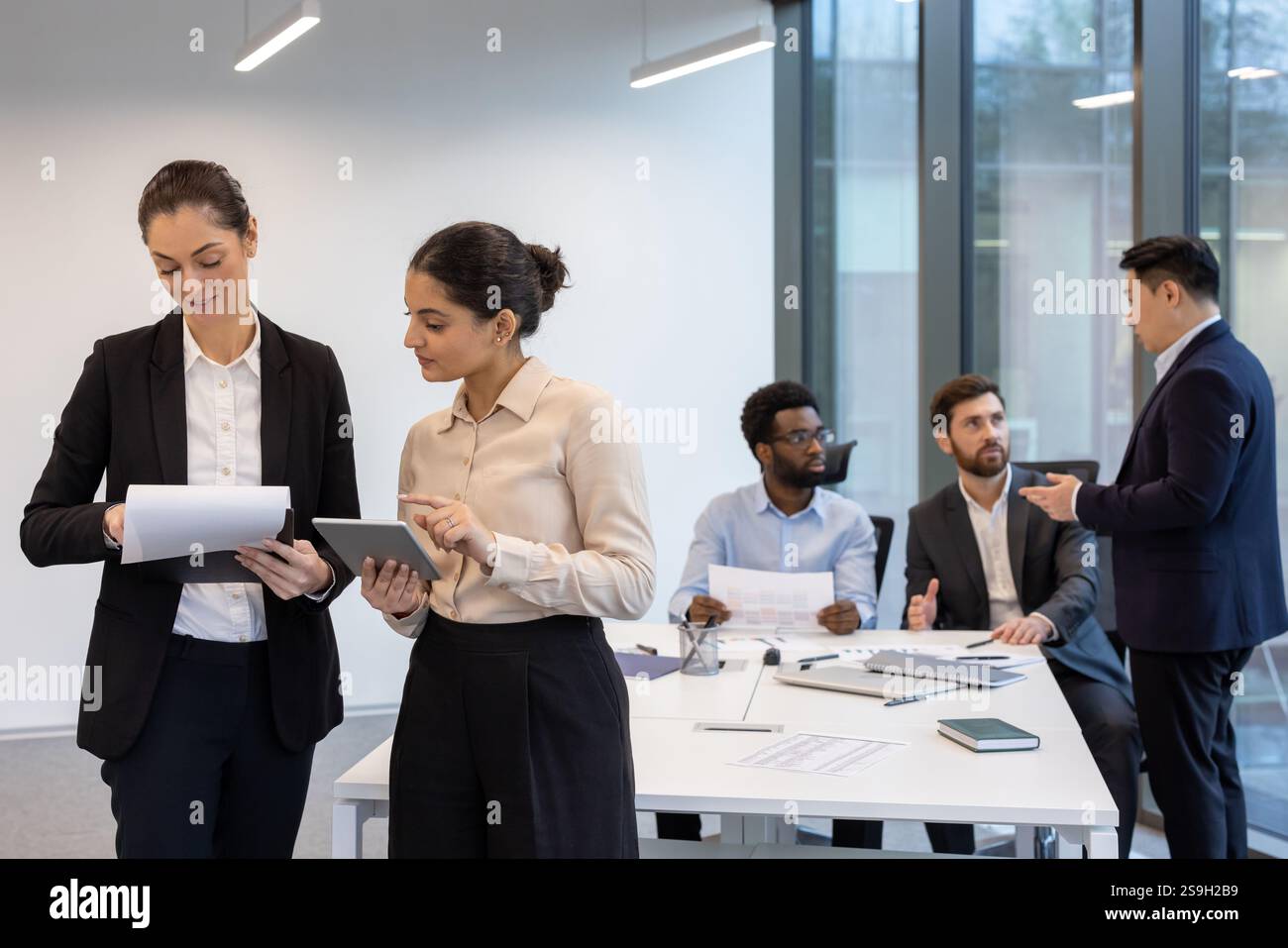 Two businesswomen standing inside the office at their workplace, office ...