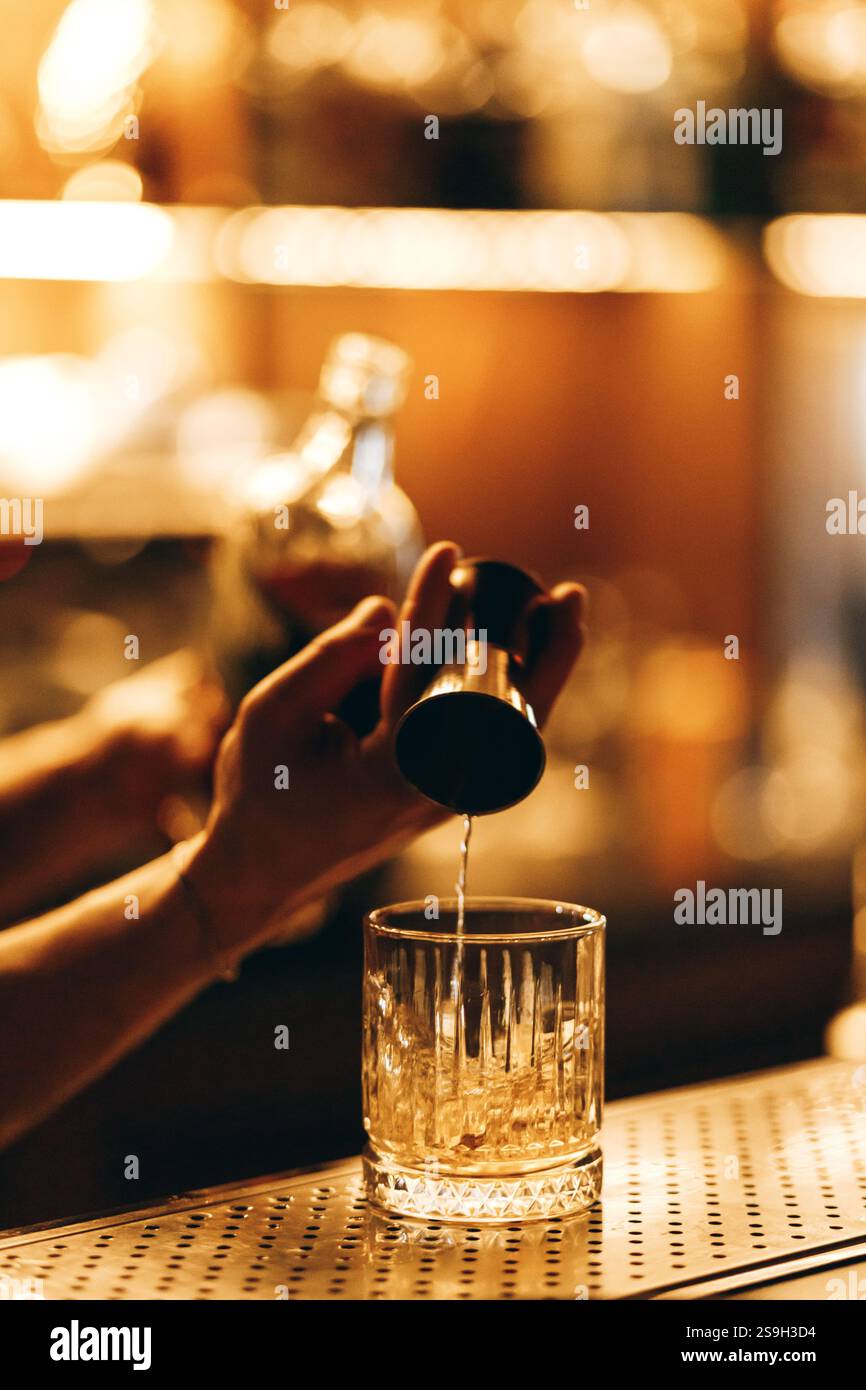Barista pouring vodka into glass from measuring cup. Preparing cocktail on bar Stock Photo - Alamy