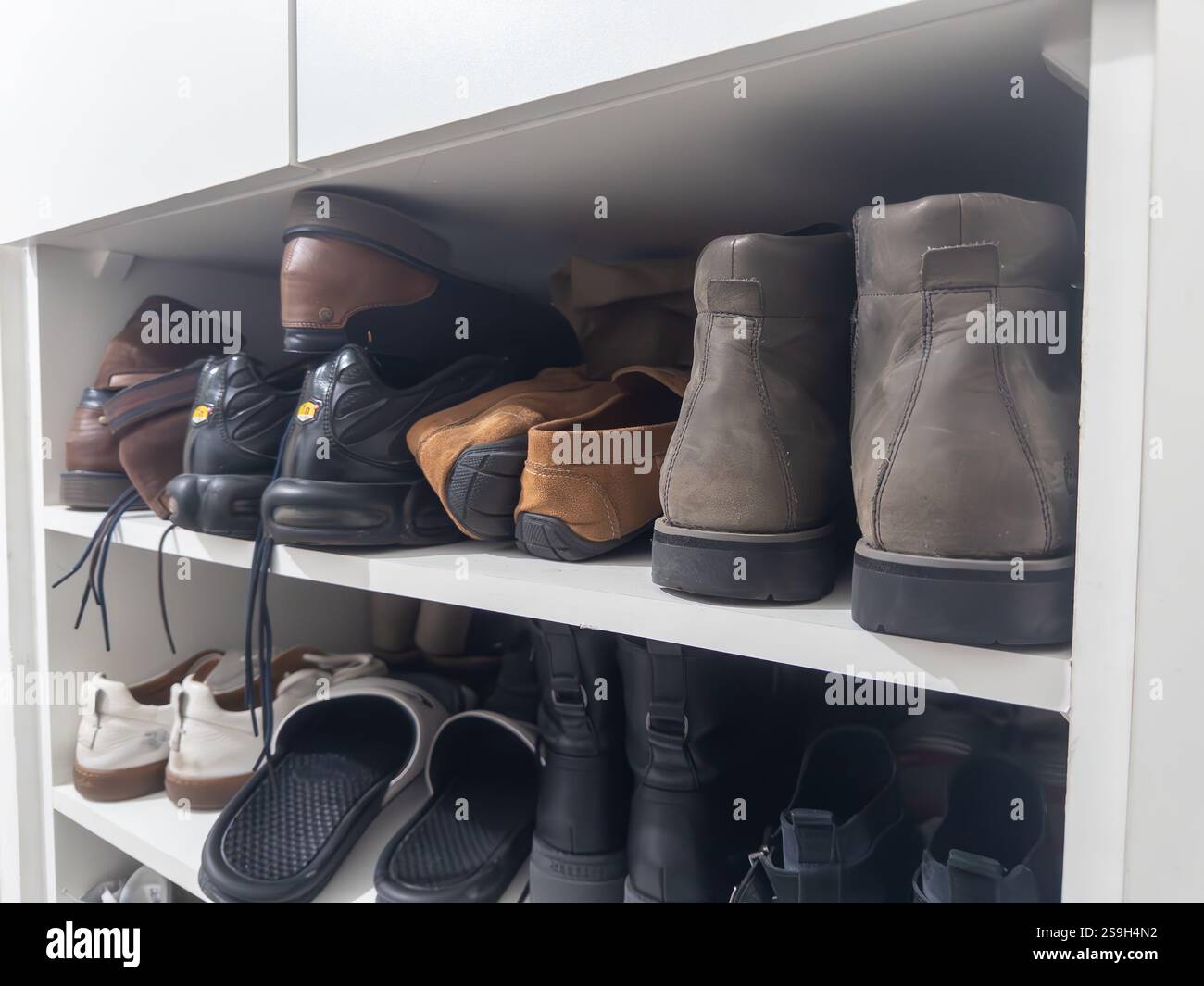 Various styles of shoes neatly arranged on white shelves in a modern ...