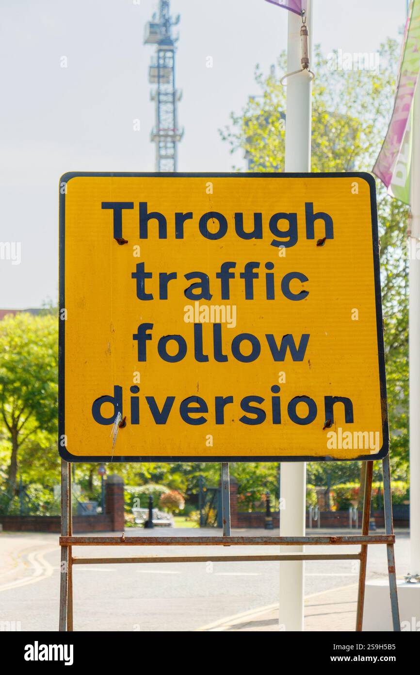 yellow warning sign "Through traffic follow diversion" in street in ...